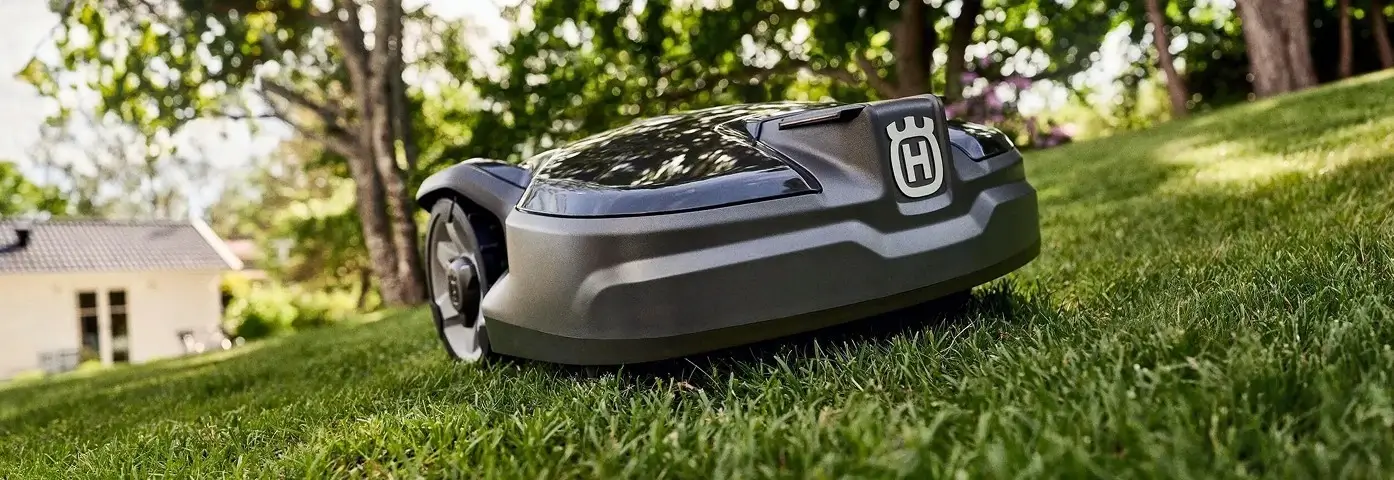 Robotická sekačka Husqvarna na svažitém trávníku u rodinného domu